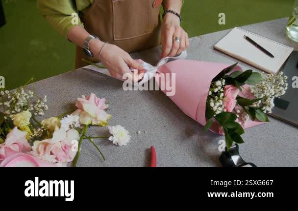 High angle view of unknown female florist tying bow with white ribbon ...
