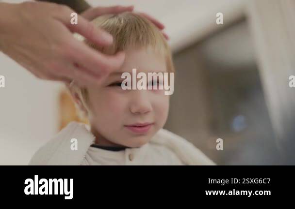 Montage of a young child receiving a haircut from a parent, showing ...