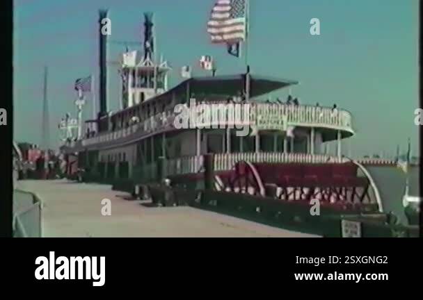 A classic paddlewheel steamboat is docked at a riverside location with ...