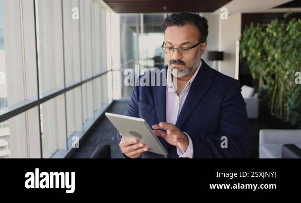 Serious senior Indian company CEO man using financial application on ...