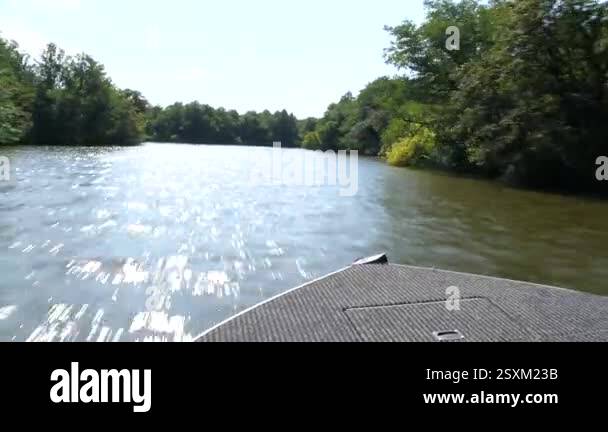 Motorboat cruising along scenic river, gliding between verdant banks ...