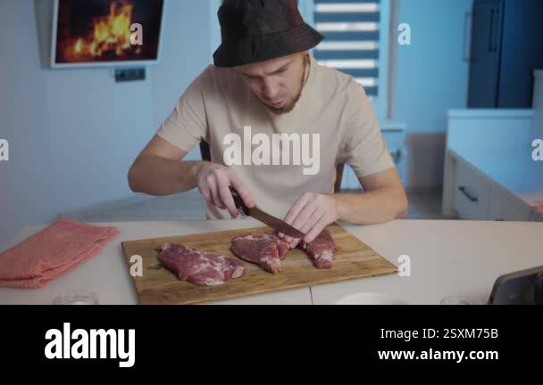 A person is skillfully slicing a piece of meat on a wooden chopping ...