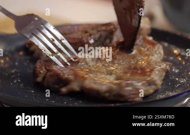 A closeup view of a perfectly seared steak being cut open with a fork ...