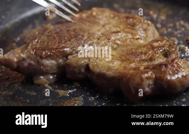 A beautifully cooked pork chop is sizzling in a frying pan, showcasing ...