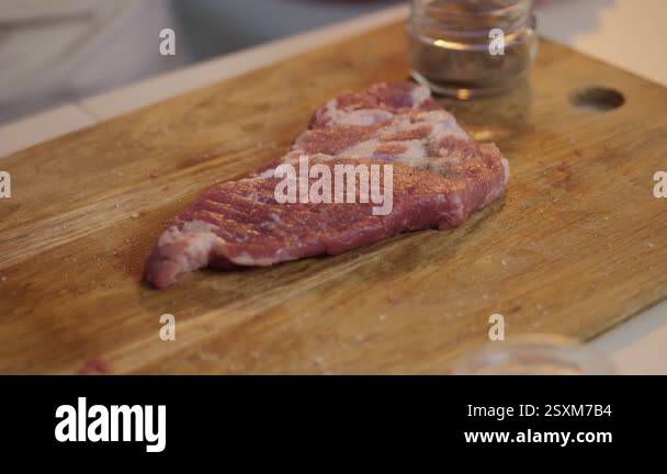 A skilled person seasoning a flavorful piece of meat on a rustic wooden ...