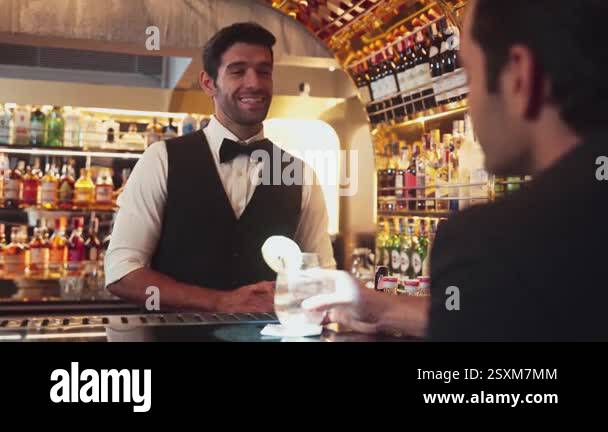 Smart bartender serving drink gin fizz with lemon sliced to VIP guest ...