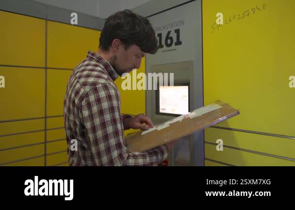 Yellow self-service postal terminal. Man sending parcel. Parcel pick up ...