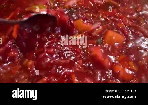 A cook stirs Ukrainian borscht in a saucepan with a spoon. The process ...