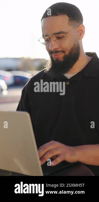 Man sporting a beard and glasses is fully concentrated on his laptop ...
