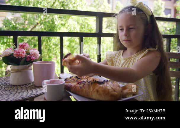 Portrait of a cute girl with long, dark hair enjoying crusty croissant ...