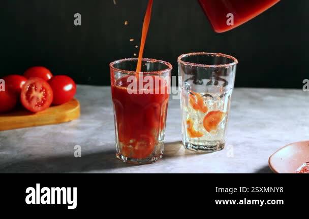 Pouring two glasses with fresh tomato juice. Garnishing glass with ...