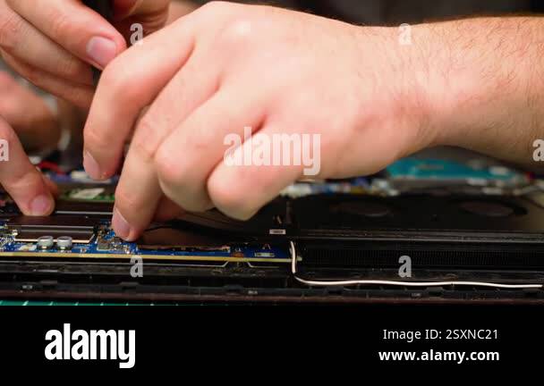 Hands repairing notebook laptop, securing components on motherboard ...