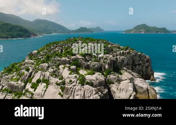 A large rocky island surrounded by turquoise waters with distant ...
