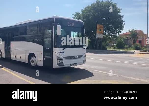 A white bus leaves the bus stop travelling along the road in Croatia ...