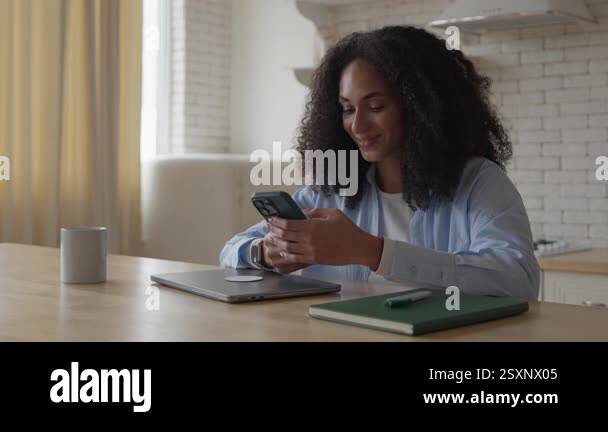 African Woman Resting Seated in Kitchen with Smart Phone Web Surfing ...