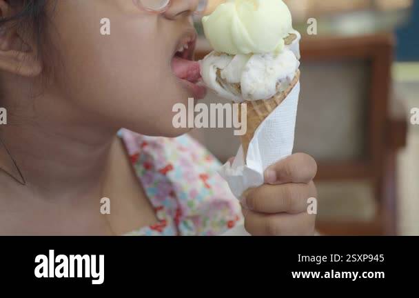 A young child savors a colorful ice cream cone at a local shop Stock ...