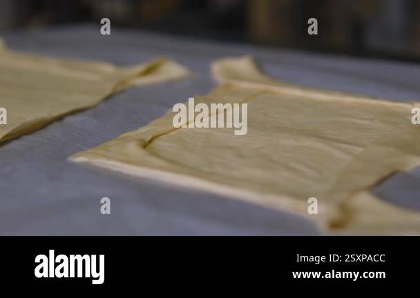 Hands rolling dough on wooden surface with rolling pin and flour nearby ...