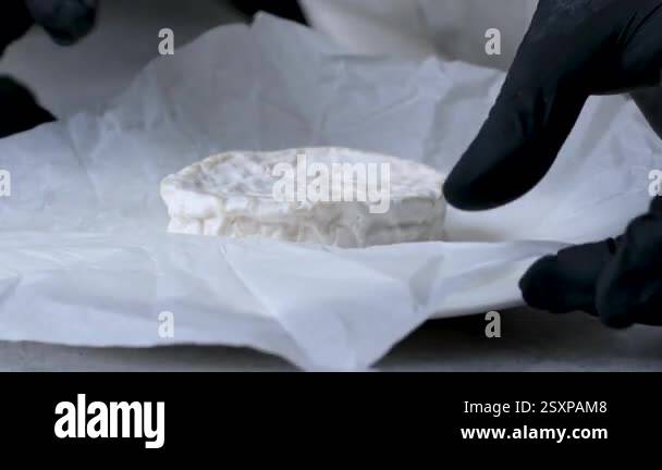 a worker at a craft cheese factory turns over cheese blanks production ...