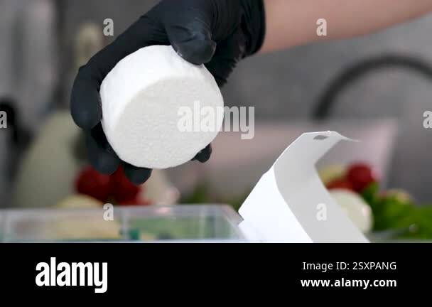 a worker at a craft cheese factory turns over cheese blanks production ...