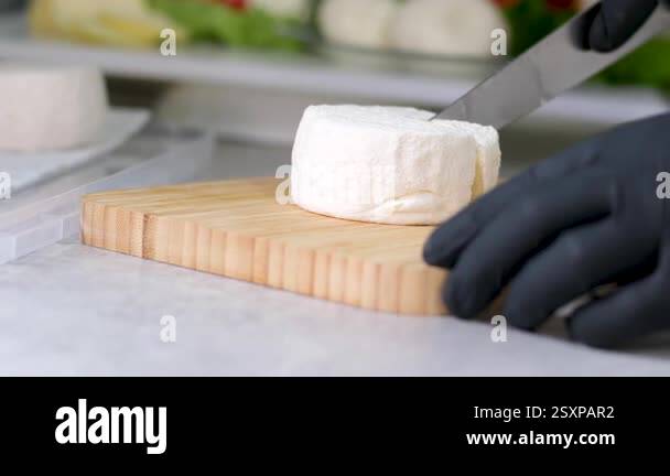 a worker at a craft cheese factory turns over cheese blanks production ...