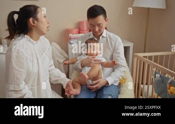 Mother and father sit in a cozy bedroom, lovingly interacting with ...