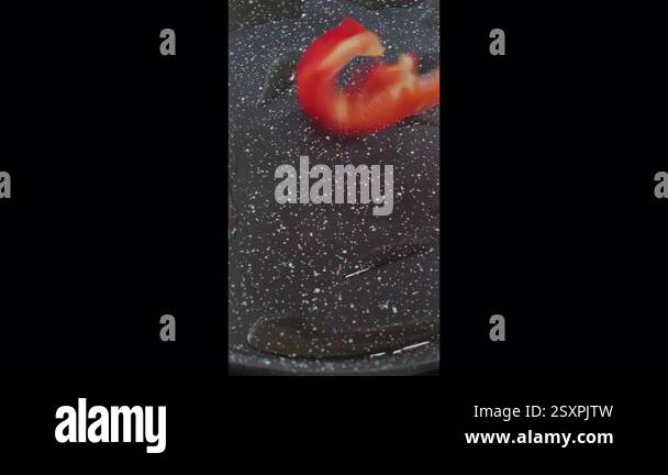 Vertical video. The cook pours red pepper into the pan. Frying the ...