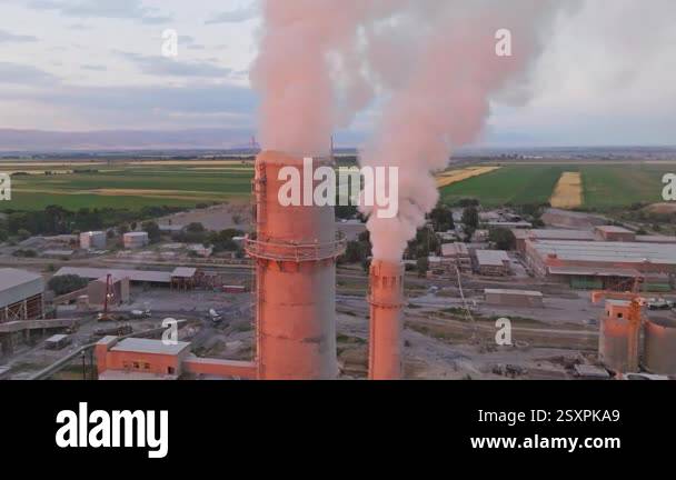 closeup aerial view of two smoking pipes of soviet concrete factory at ...