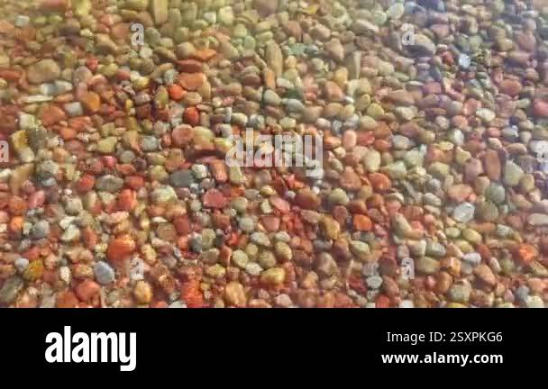 colorful round rocks at the beach lit by sun light through thin layer ...
