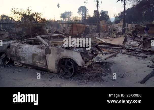 A striking and vivid scene of devastation features a charred car set in ...