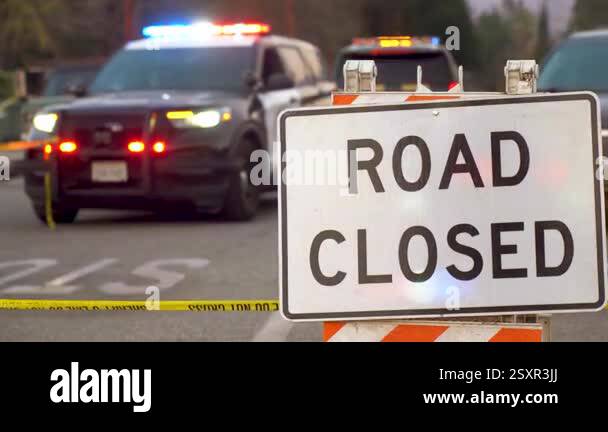 A detailed scene of a road closure enforced by law enforcement vehicles ...