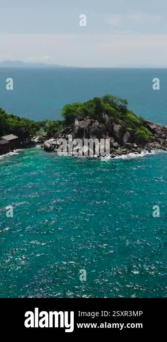 Small island with dense green vegetation surrounded by turquoise waters ...