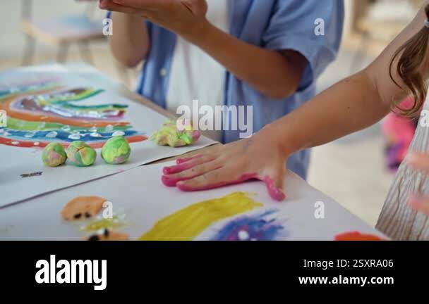 School girl painting with hand creating palm prints on paper closeup ...