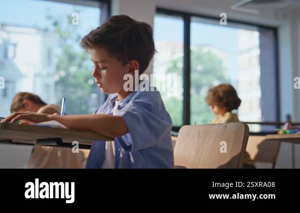 Elementary school pupils writing in copybooks sitting desks. Group ...