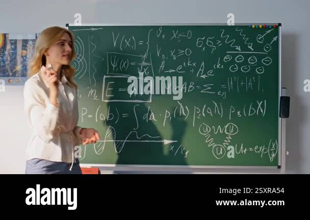 Elegant woman teaching physics equations in classroom. Blonde teacher ...