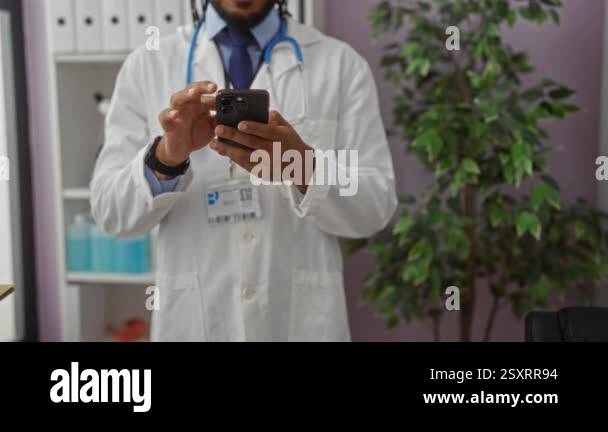 Doctor with braids using smartphone in hospital office, wearing a ...