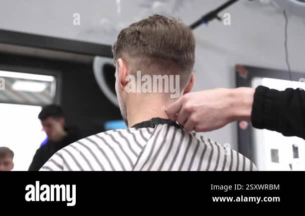 Professional barber shaving neck hairline of male customer with a ...