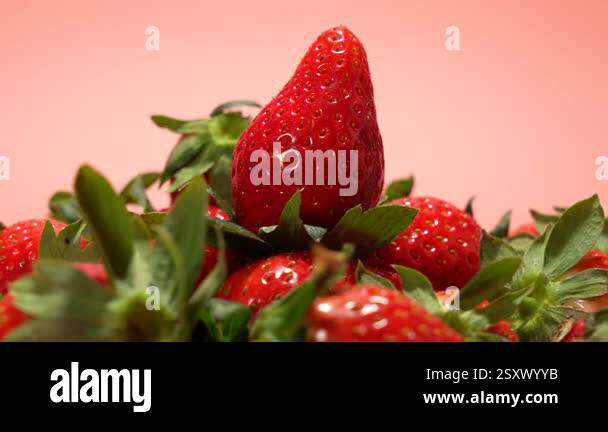 A red strawberry sits on a bunch of other red strawberries and rotates ...