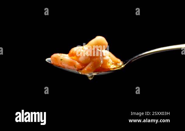 A spoonful of shrimp is on a spoon. The shrimp are in a pile on the ...