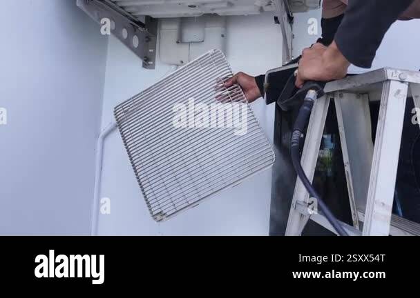 A technician rinsing a wall mounted air conditioner and fixing HVAC ...