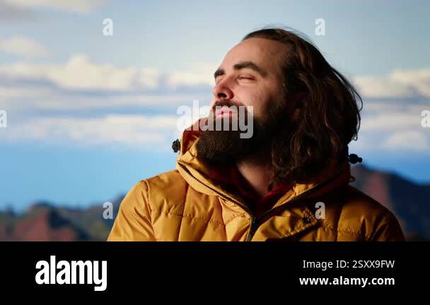 Young adult trekker camping with his tent on a mountain top battling ...