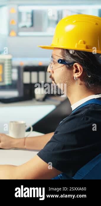 Vertical video Photovoltaics factory engineer wearing yellow hardhat analyzing data, reviewing ...
