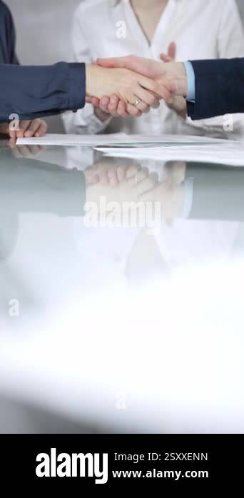Business partners shaking hands after signing contract at glass table ...
