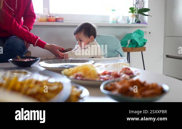 Curious baby exploring ingredients while preparing a pizza with his ...