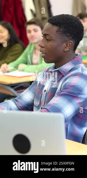 Young male student actively participating in a university class ...