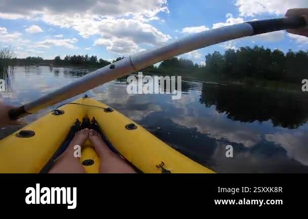 Person floating in an inflatable boat and rowing oar along small river ...