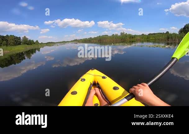 Person floating in an inflatable boat and rowing oar along small river ...