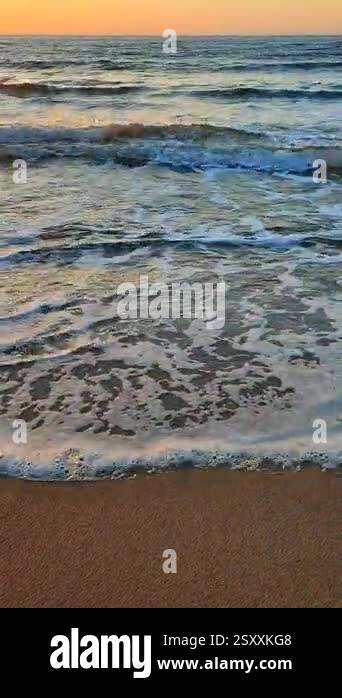 Rolling sea waves with white foam on the sandy beach of the seashore on ...
