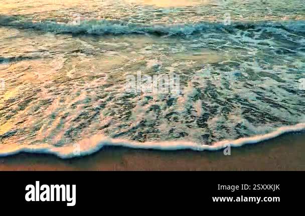 Rolling sea waves with white foam on the sandy beach of the seashore on ...