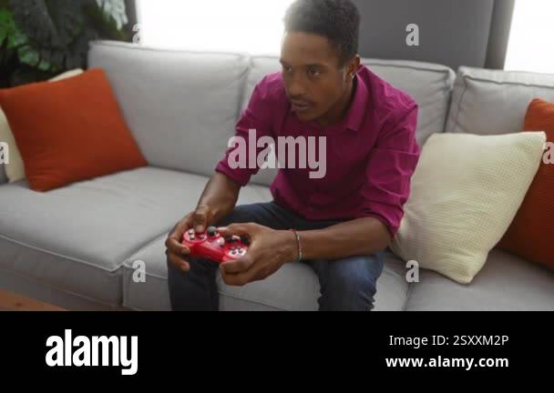 Young man playing video games on sofa in cozy living room focused on ...