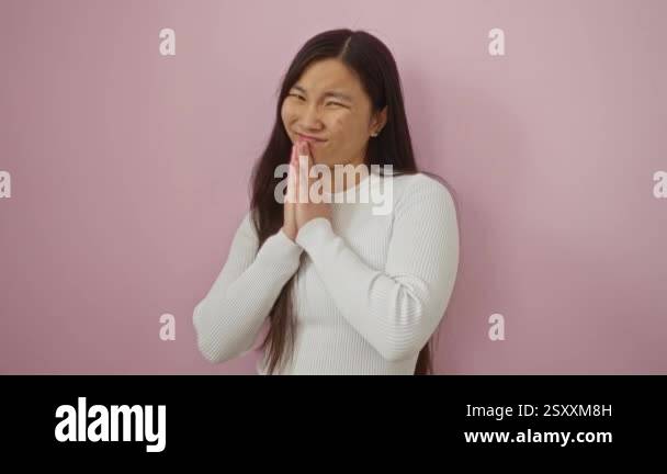 Woman doing gesture of please with hands together over isolated pink ...